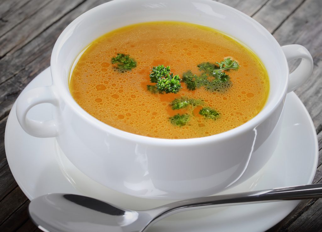 Chicken broth in a white soup cup
